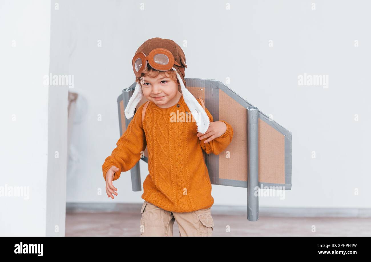 Little boy in retro pilot uniform running with toy plane indoors Stock ...