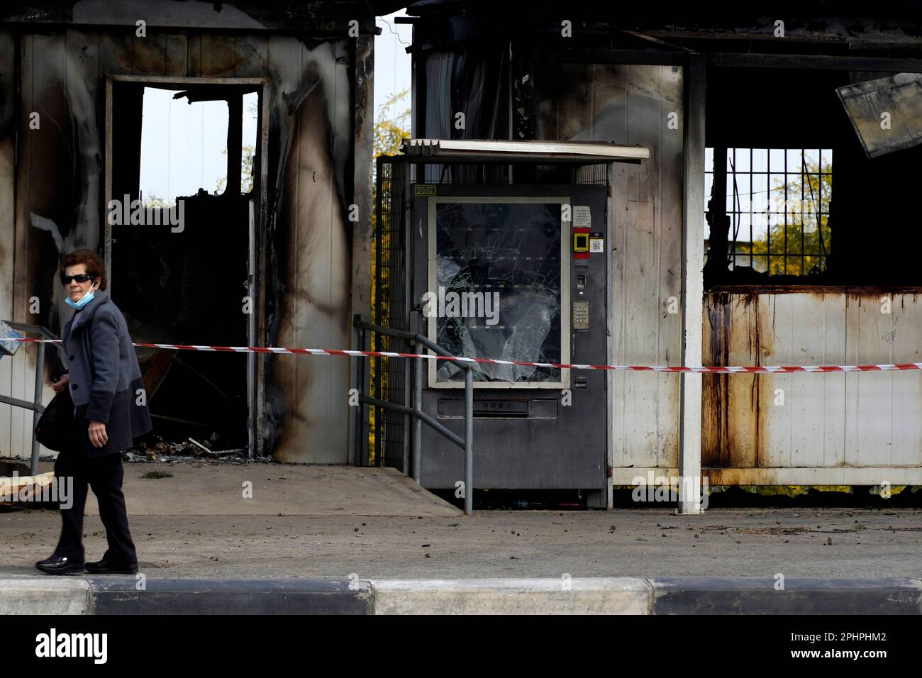 A woman walks outside of the burnt public bus office next of the ...