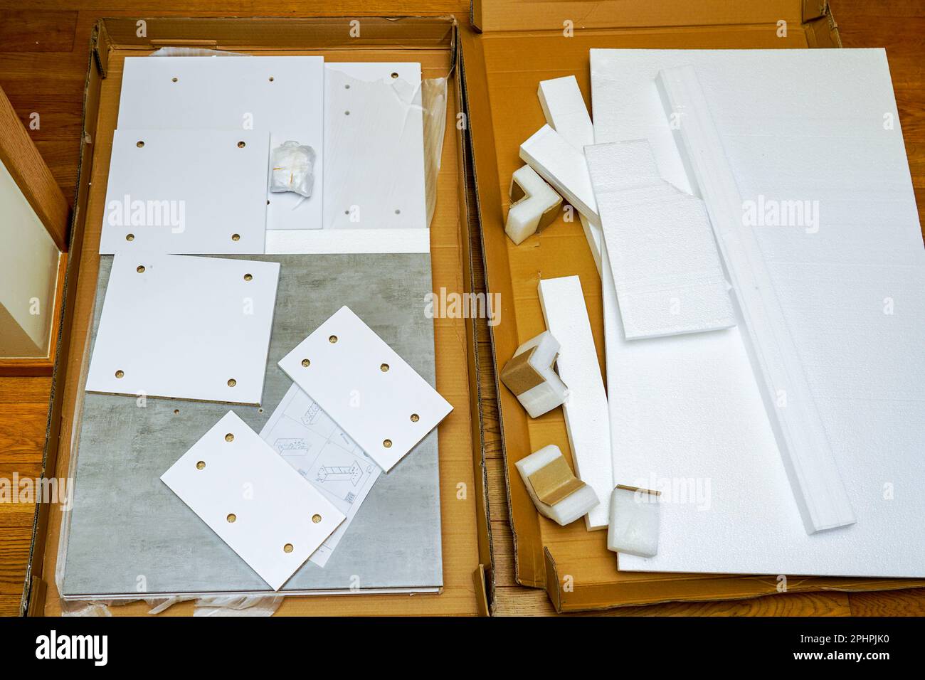 Opened cardboard box with new white and gray laminated chipboard set ...