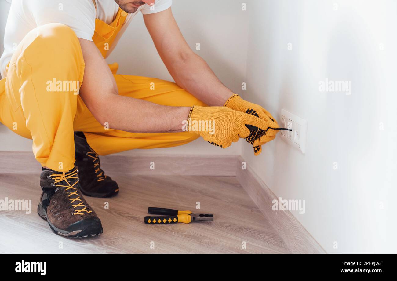 Handyman in yellow uniform works with electricity and installing new ...