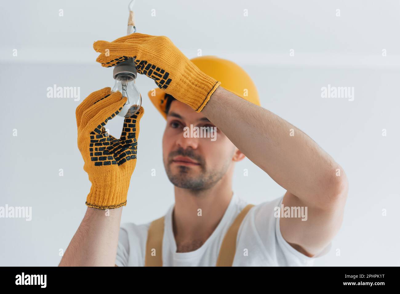 Handyman in yellow uniform changing light bulb. House renovation ...