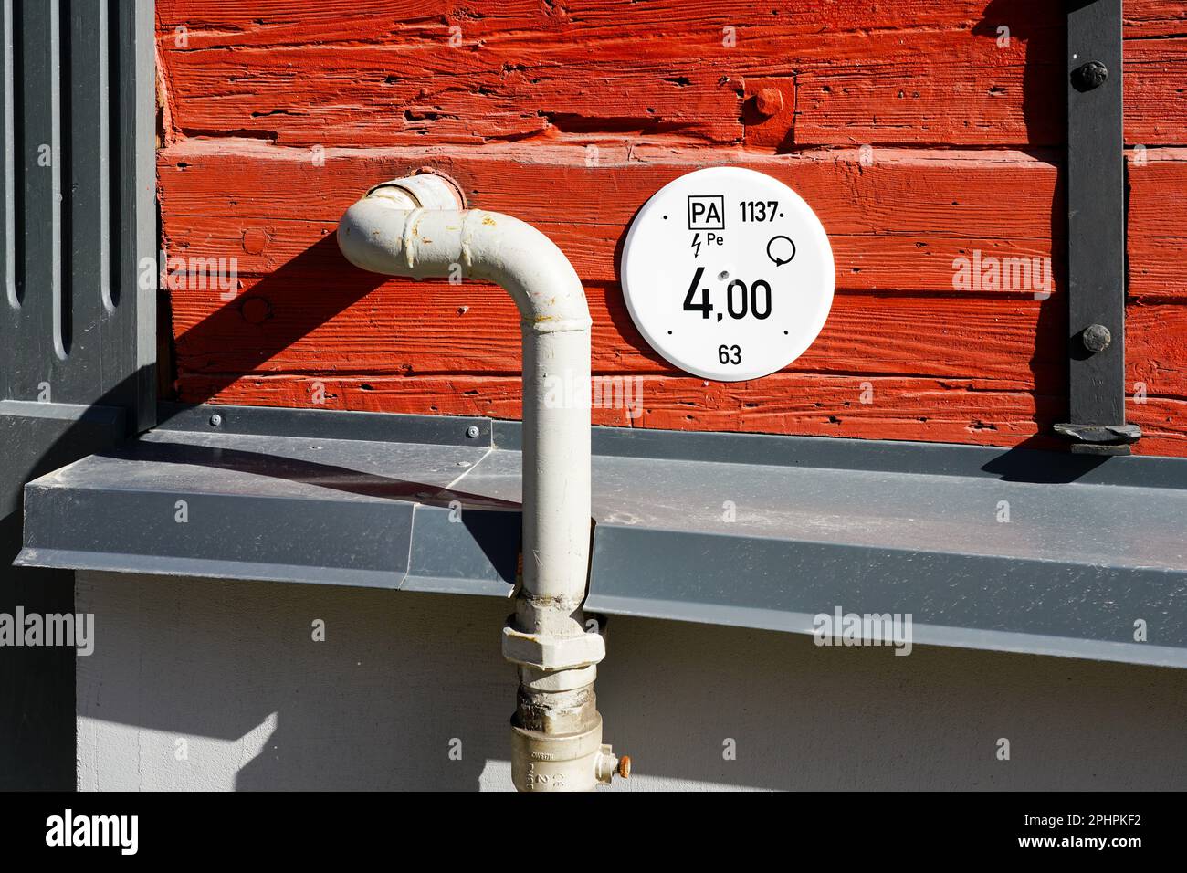 A round white metallic information plate on the wooden house facade ...