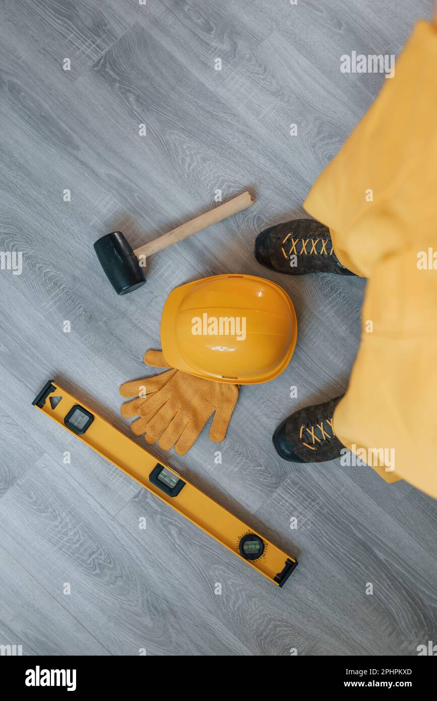 Tools on the floor. Handyman in yellow uniform standing indoors. House ...