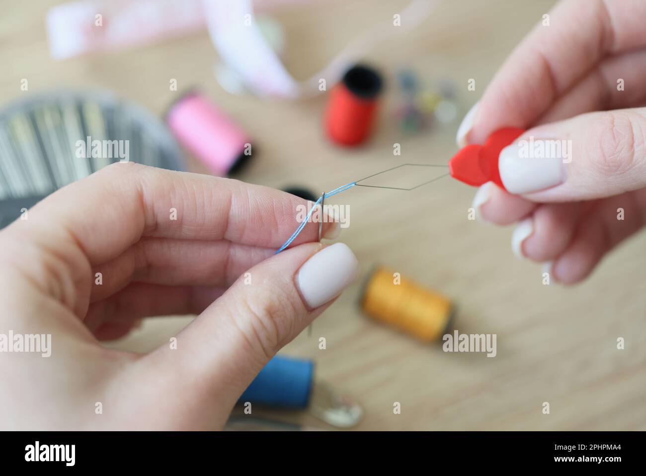 Hands of woman using special tool for threading blue needle Stock Photo ...