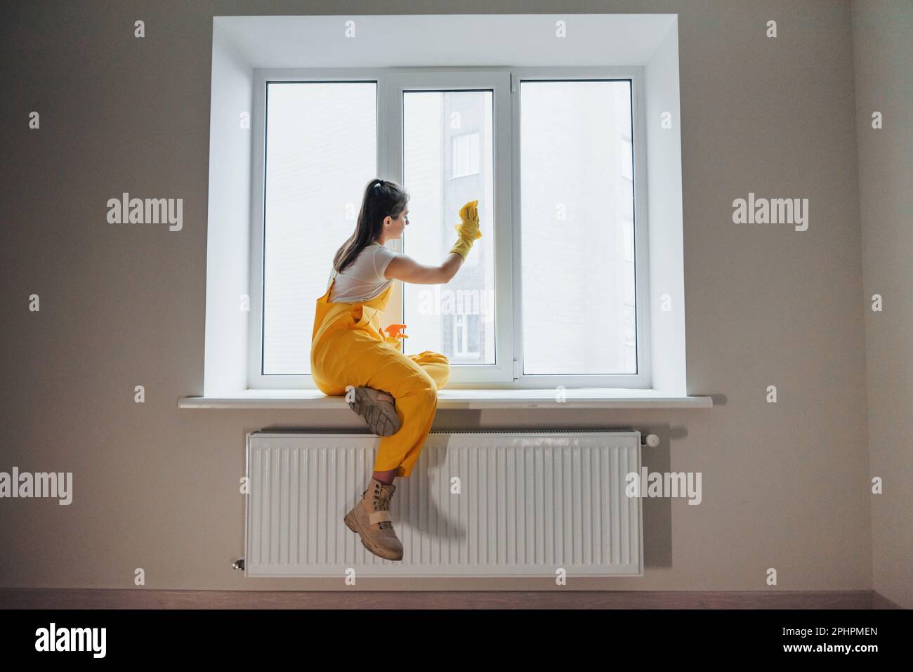 Housewife in yellow uniform cleaning windows. House renovation ...