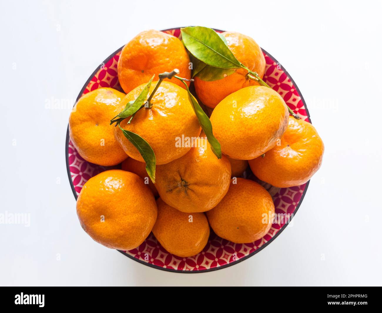 Small citrus fruits with deep orange-red skin in a red bowl Stock Photo ...