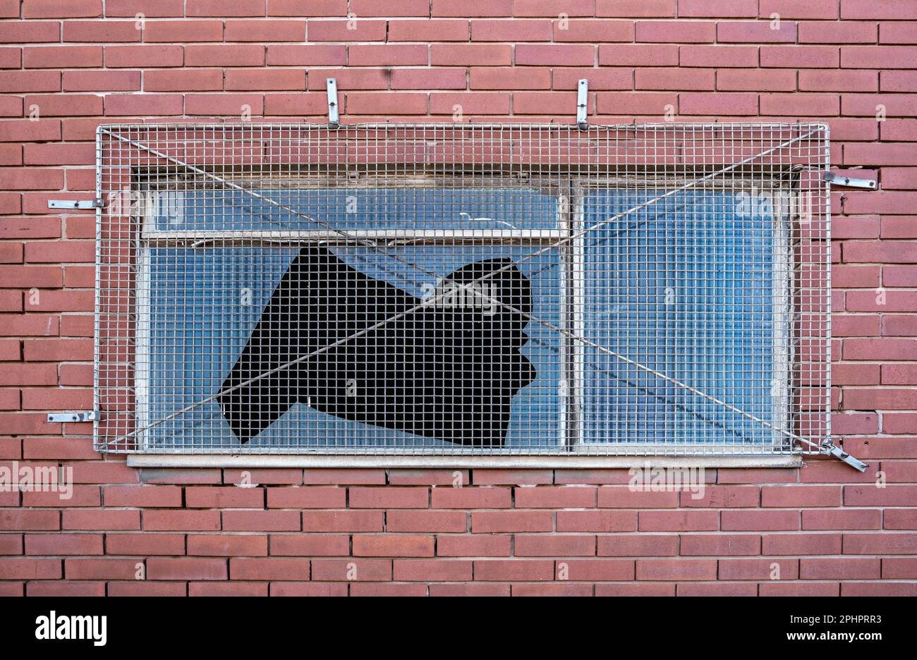 Broken warehouse window protected by metal perforated security grill ...