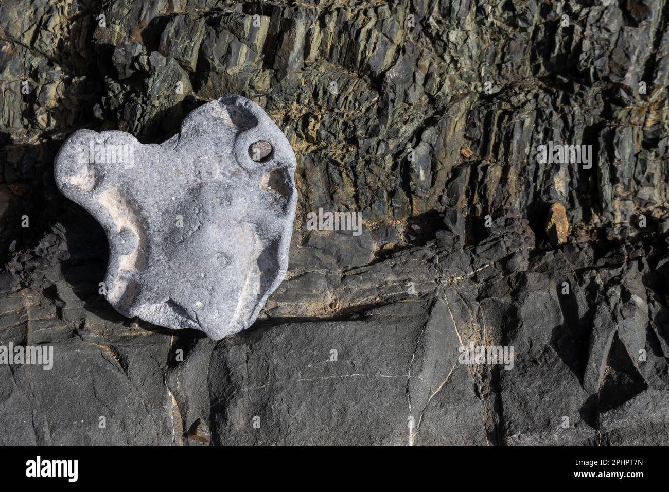 Black structured natural wall of a rock and a washed piece of metal in ...