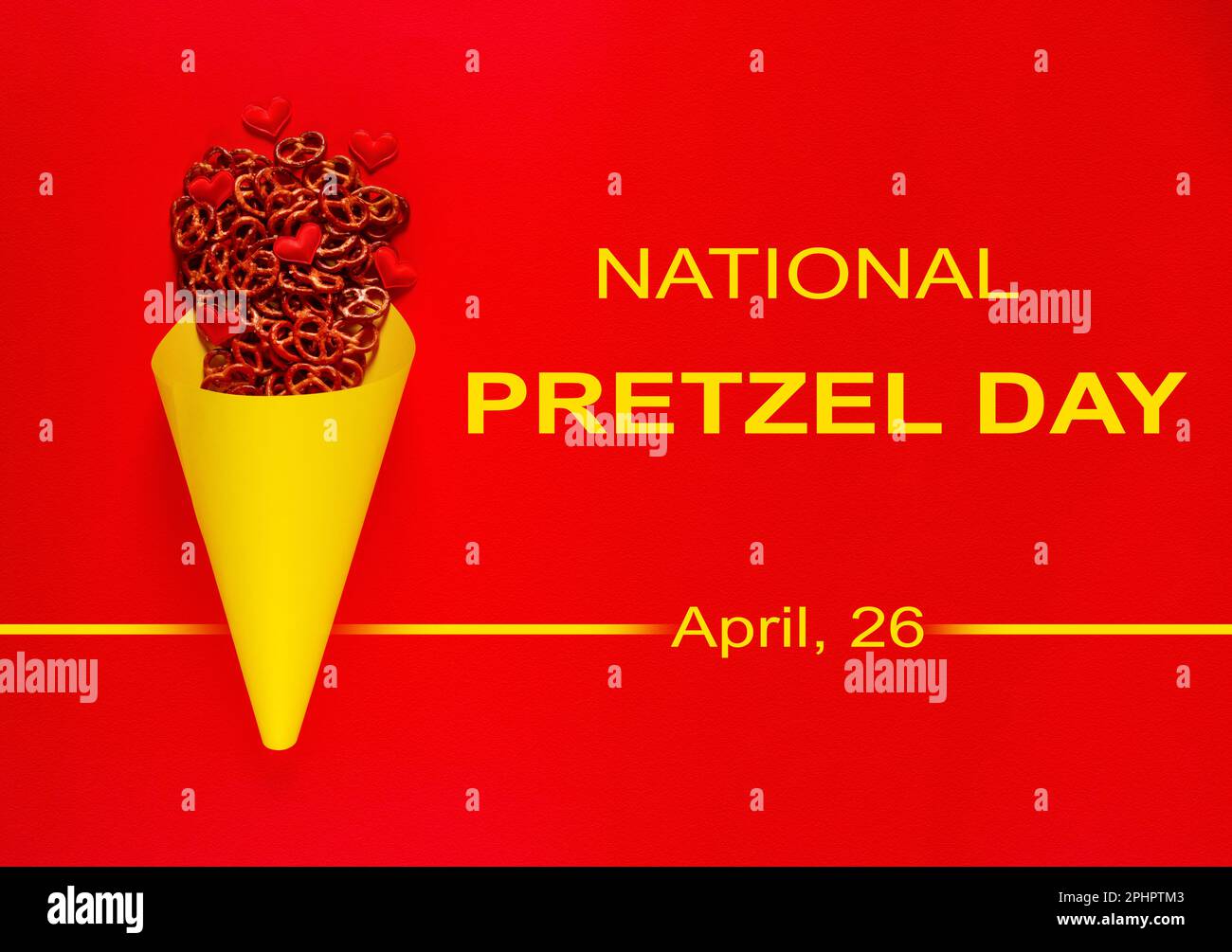Mini pretzels and small colorful hearts in yellow paper cone lie on red ...