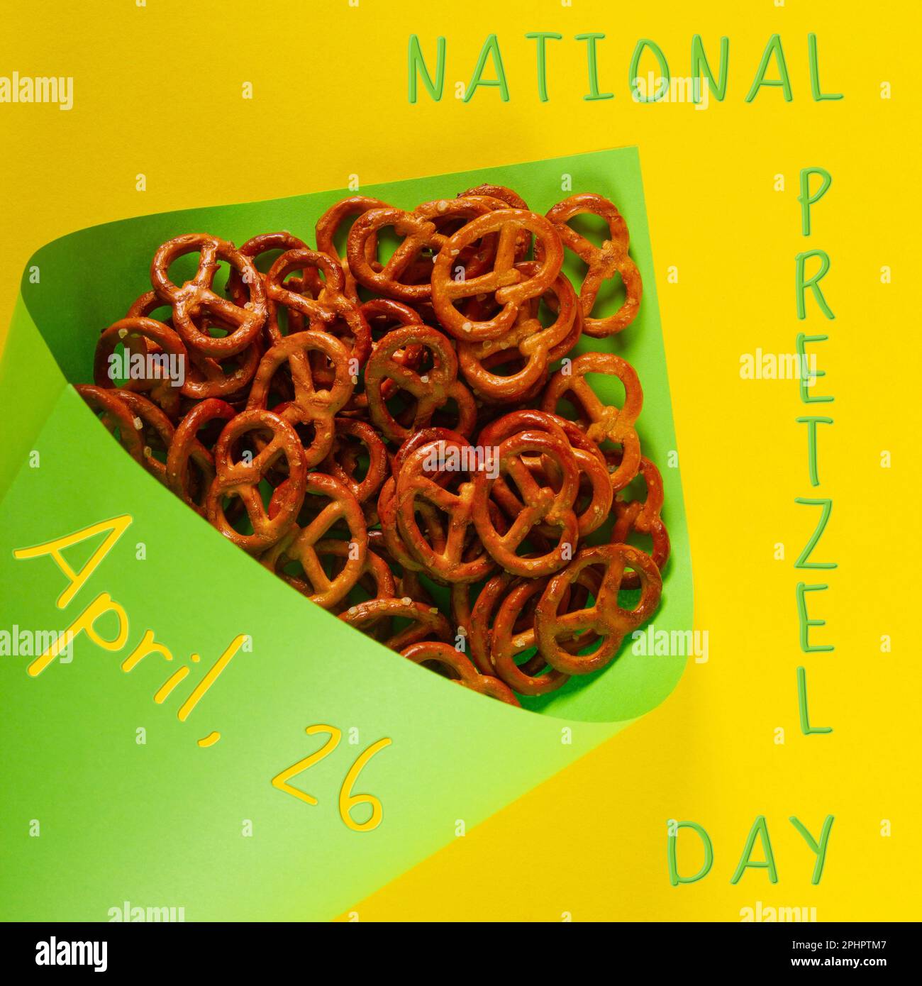 Close-up of Mini pretzels in light green paper cone lie on yellow ...