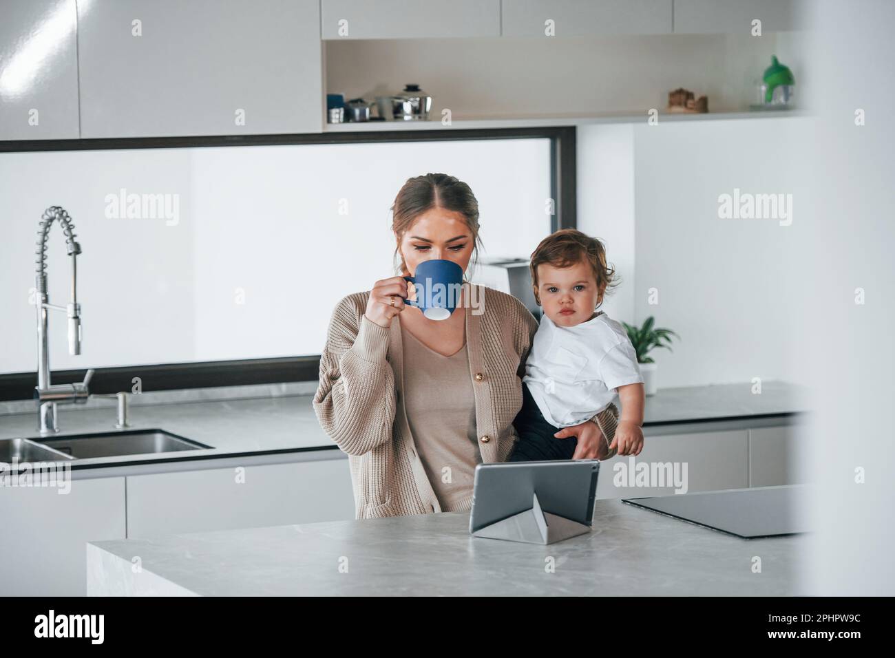 Female blogger mother with her kid together indoors at home at weekend ...