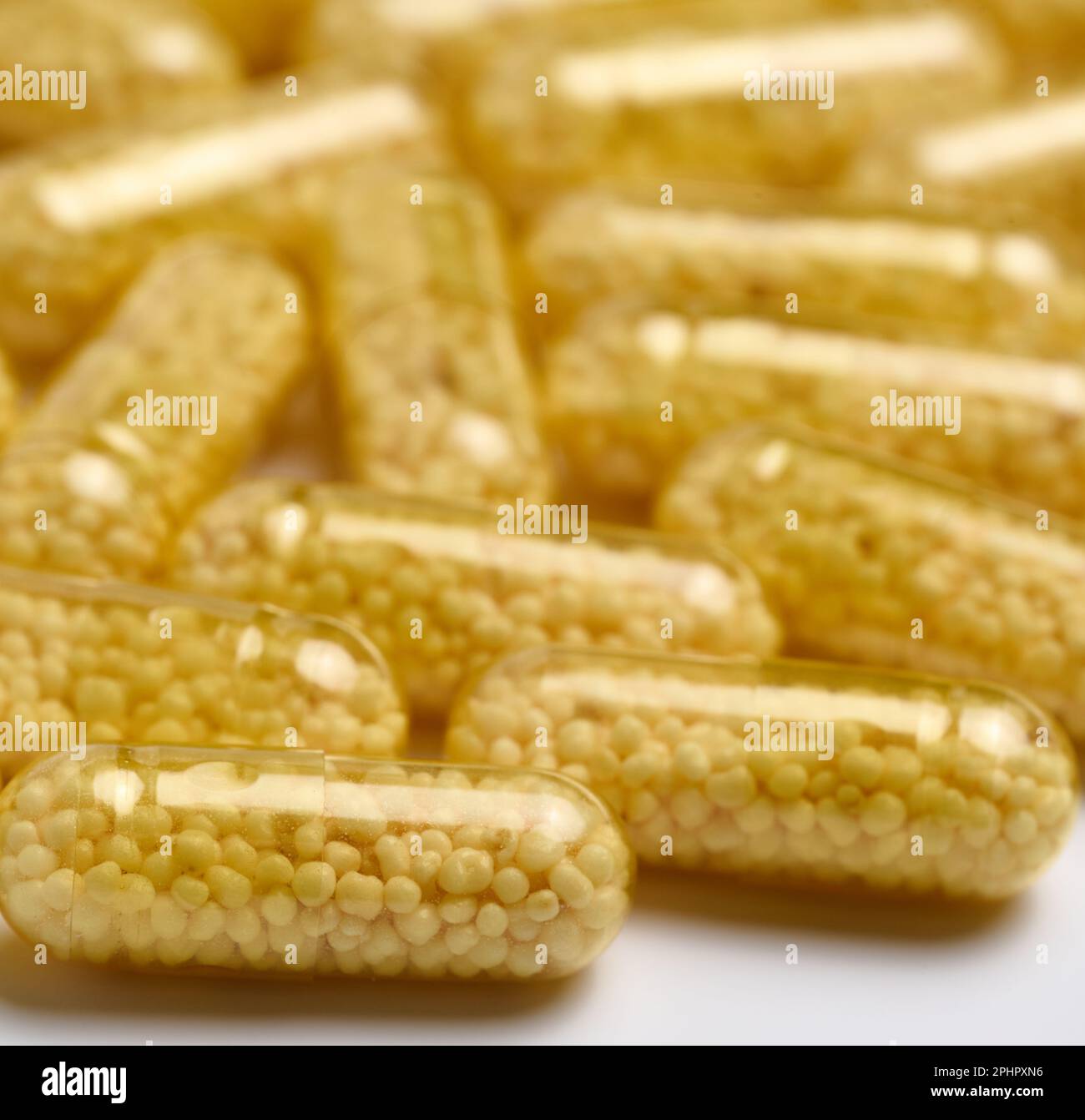 Transparent medical capsules with yellow granules inside on a white ...