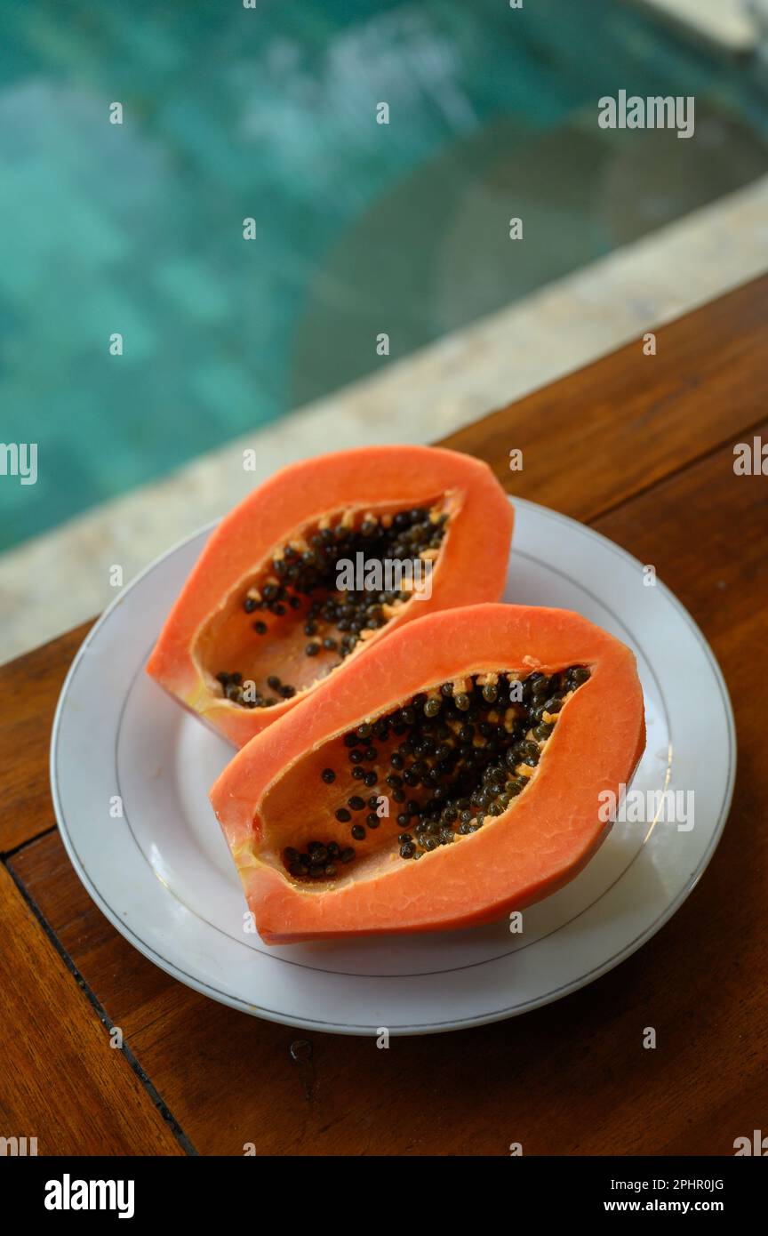 Two halves of peeled papaya in plate near swimming pool Stock Photo - Alamy