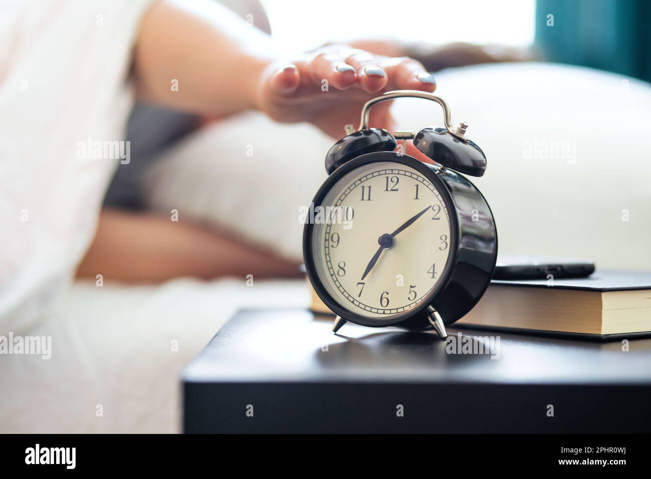 Woman on the bed reaches her hand to turn off the alarm clock Stock ...