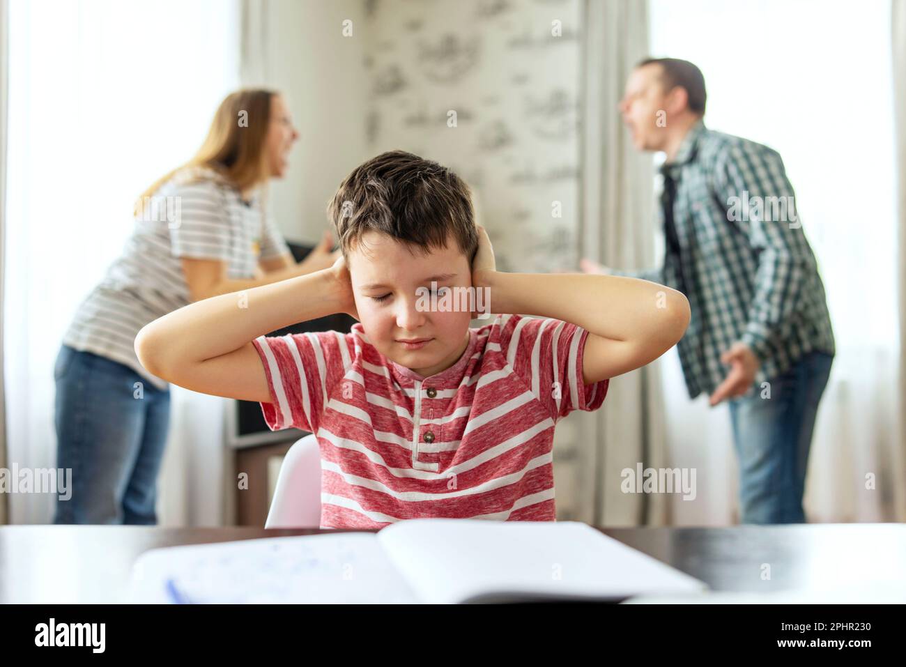 Sad child covers his ears with his hands during an argument between his ...