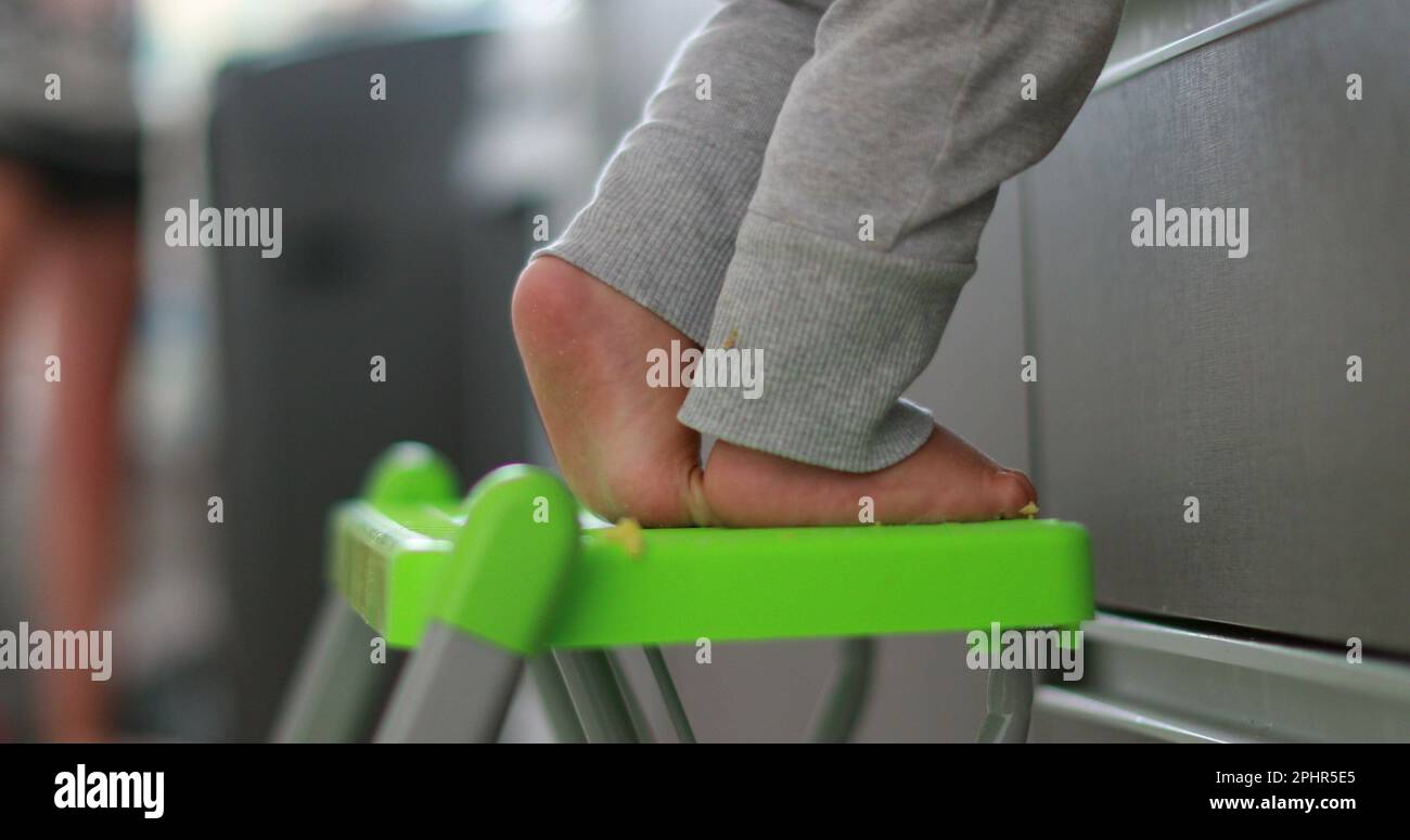 Child on tiptoes at kitchen helping mother. Infant one year old baby ...