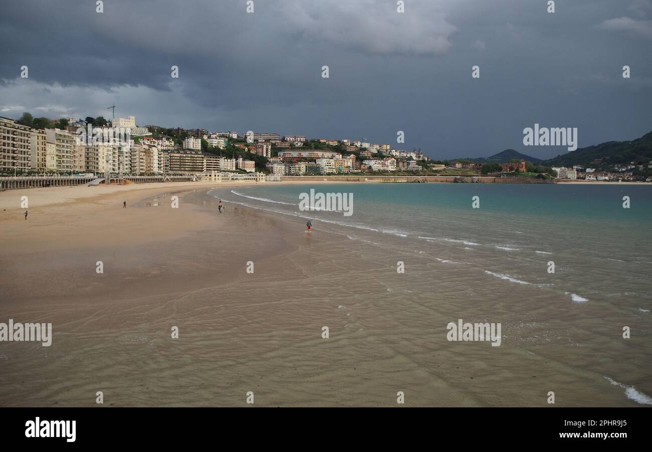 The town's waterfront, sandy beach of La Concha Bay, stormy clouds in ...