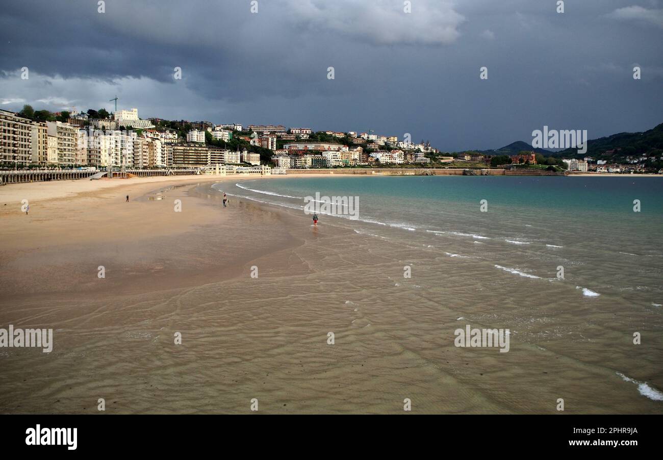 The town's waterfront, sandy beach of La Concha Bay, stormy clouds in ...