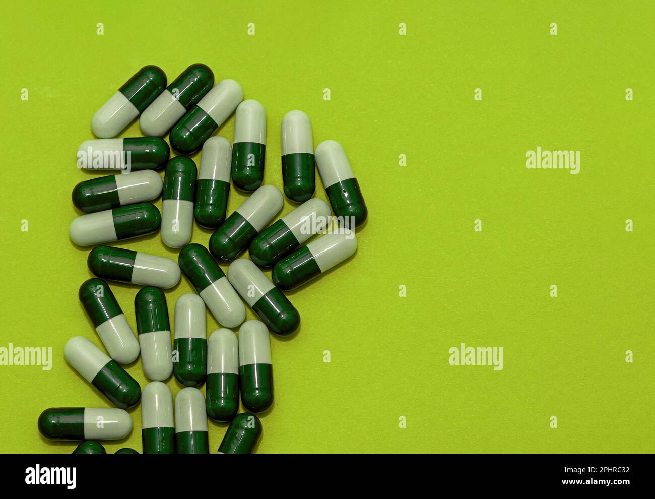 White green medical capsules pile in the corner on lime green colour ...