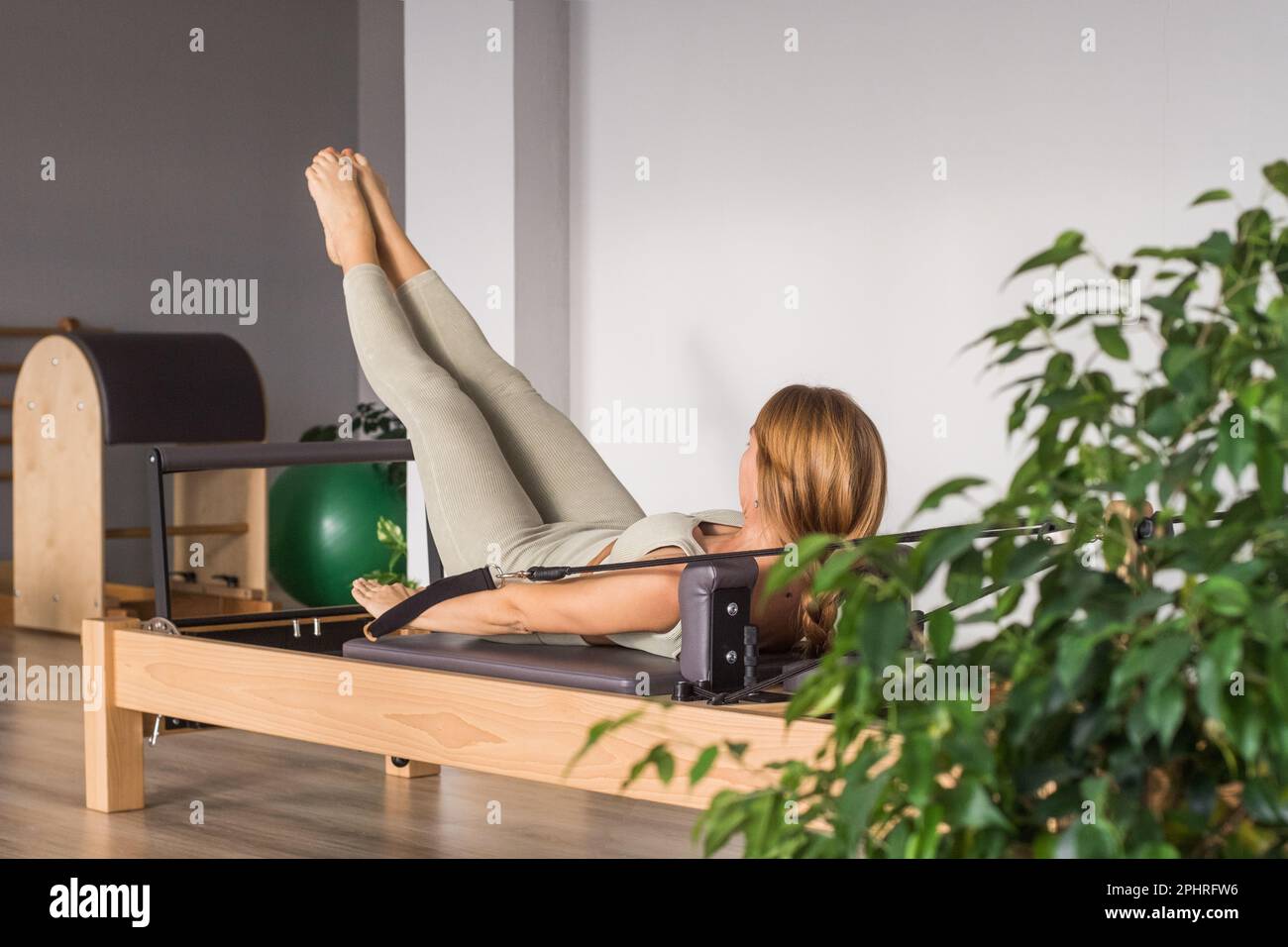 Woman training pilates on the reformer bed. Reformer pilates studio ...