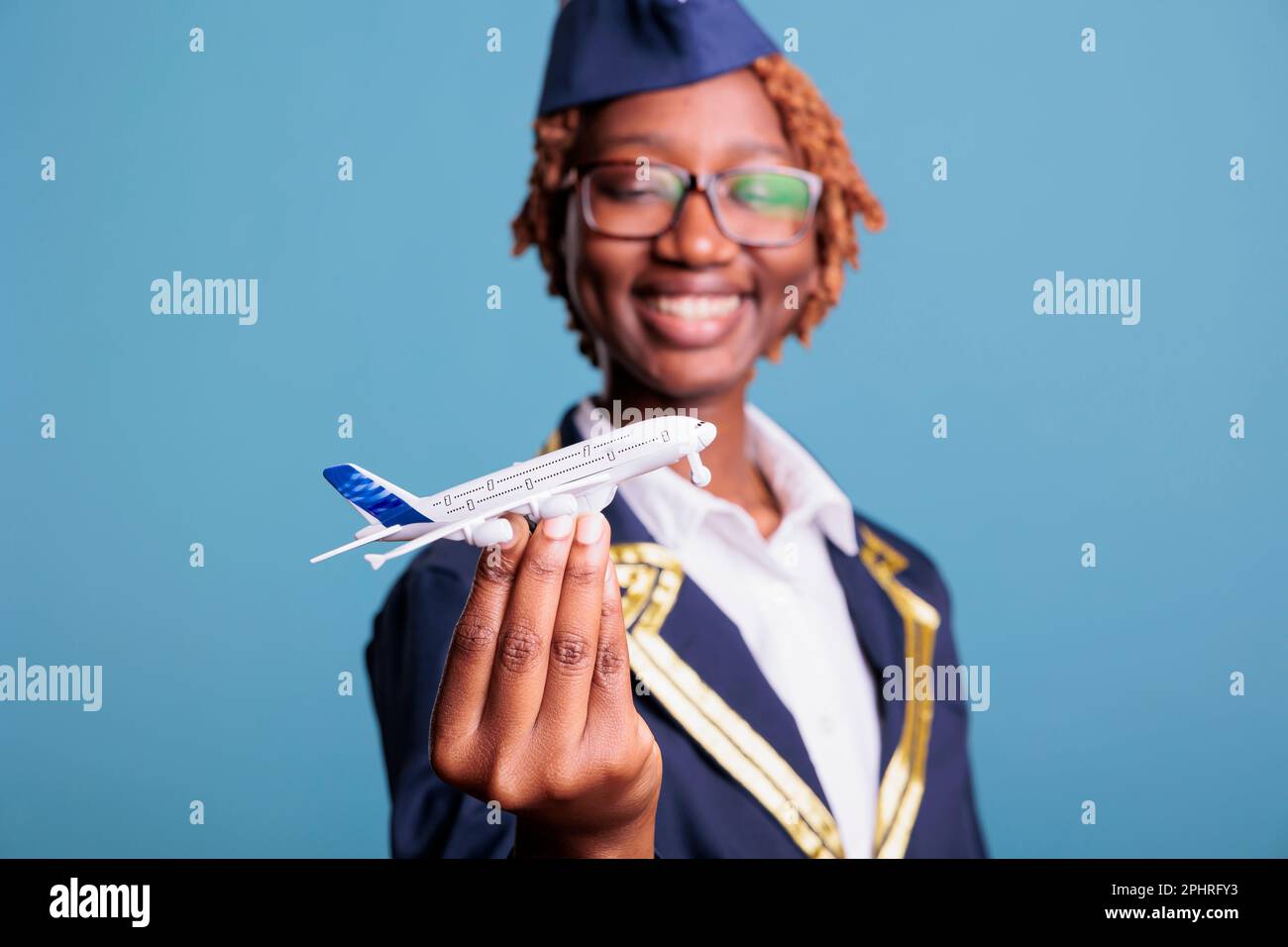 Optimistic african american flight attendant in uniform playing with ...