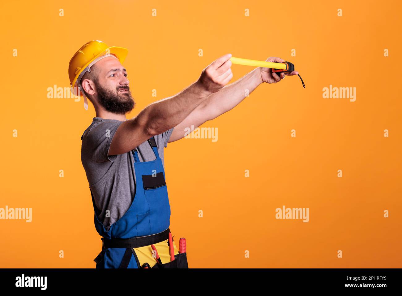 Confident construction worker using tape measure to take measurements ...