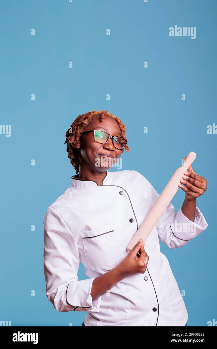 Young african american baker, using glasses happily showing off rolling ...