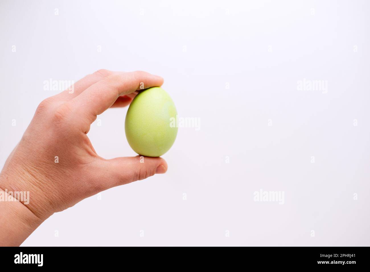 Human hand holds light green Easter egg on an isolated white background ...