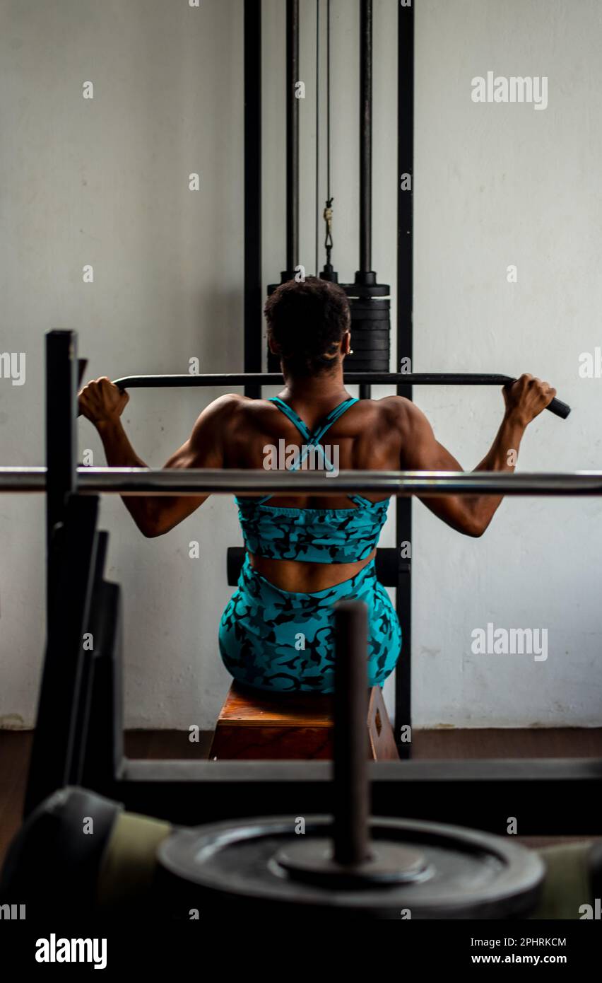 Portrait of muscular woman doing pull-up exercises for back muscles ...