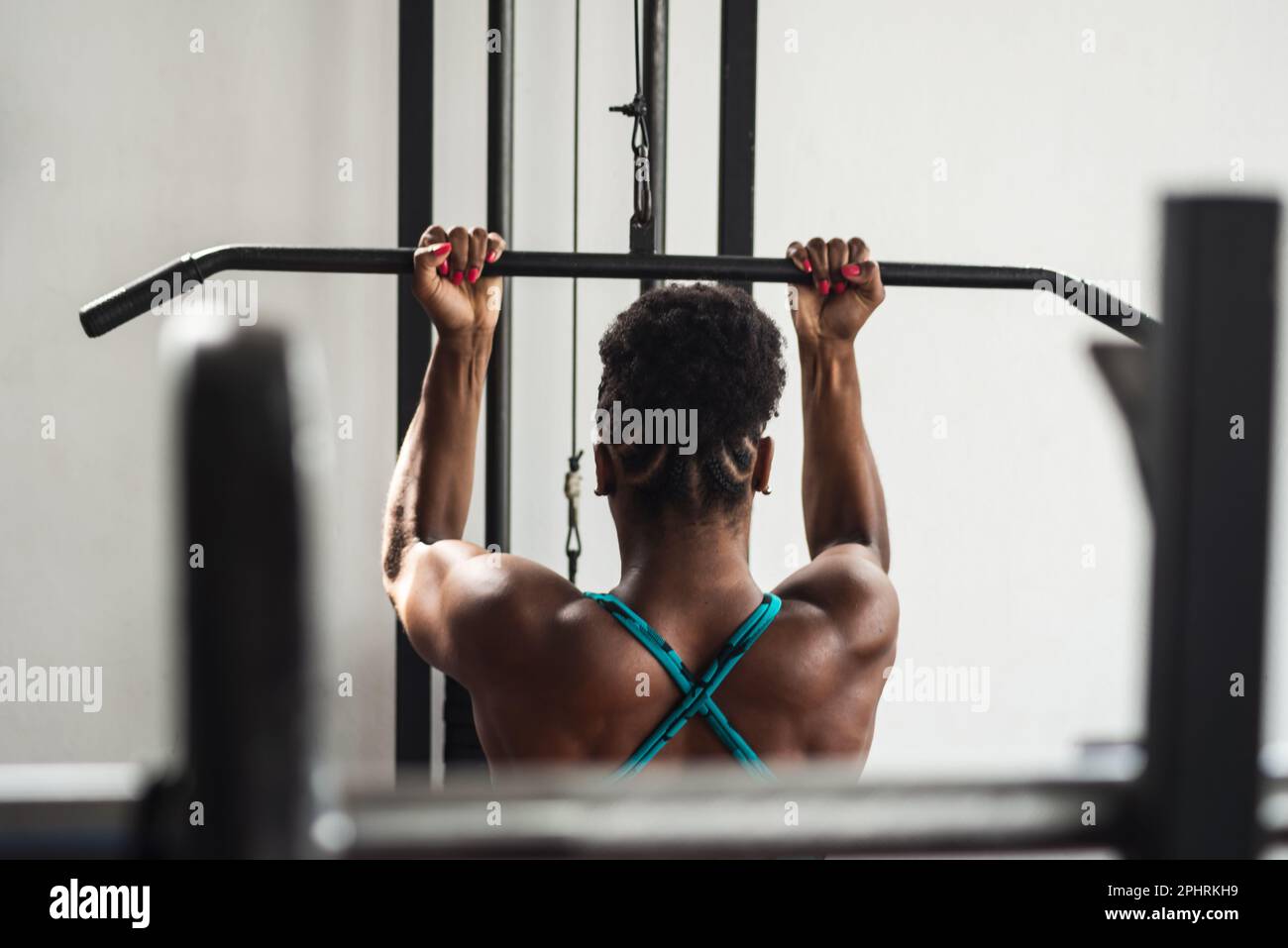 Portrait of muscular woman doing pull-up exercises for back muscles ...