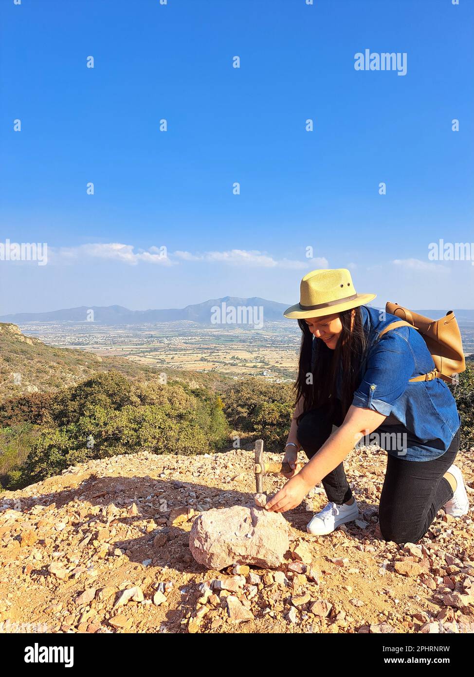 Latina woman with hat and miner's pick hammer works as a geologist ...