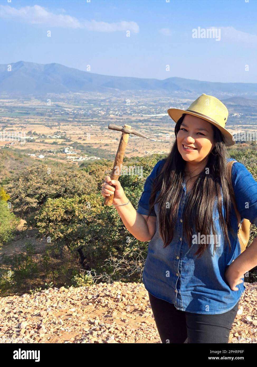 Latina woman with hat and miner's pick hammer works as a geologist ...