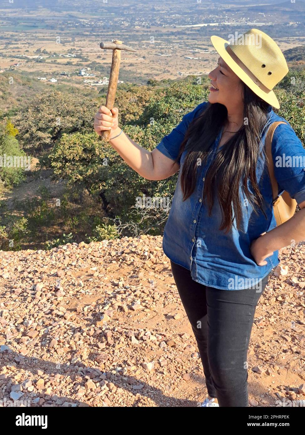 Latina woman with hat and miner's pick hammer works as a geologist ...