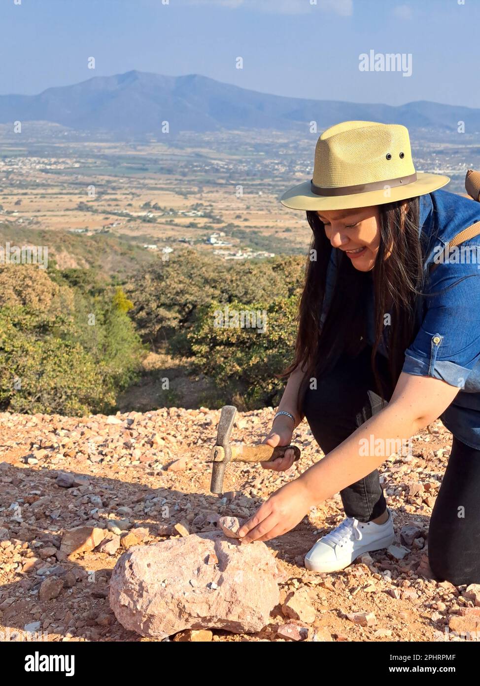 Latina woman with hat and miner's pick hammer works as a geologist ...