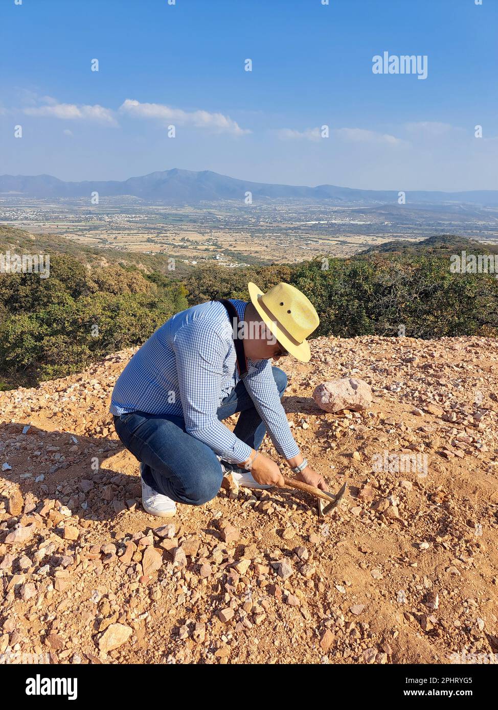 Latin man with hat and miner's pick hammer works as a geologist ...