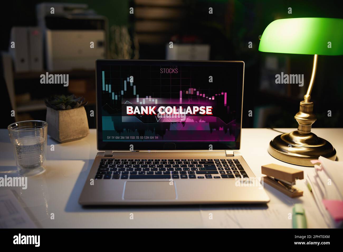 desk with laptop with bank collapse screen at night in the modern ...