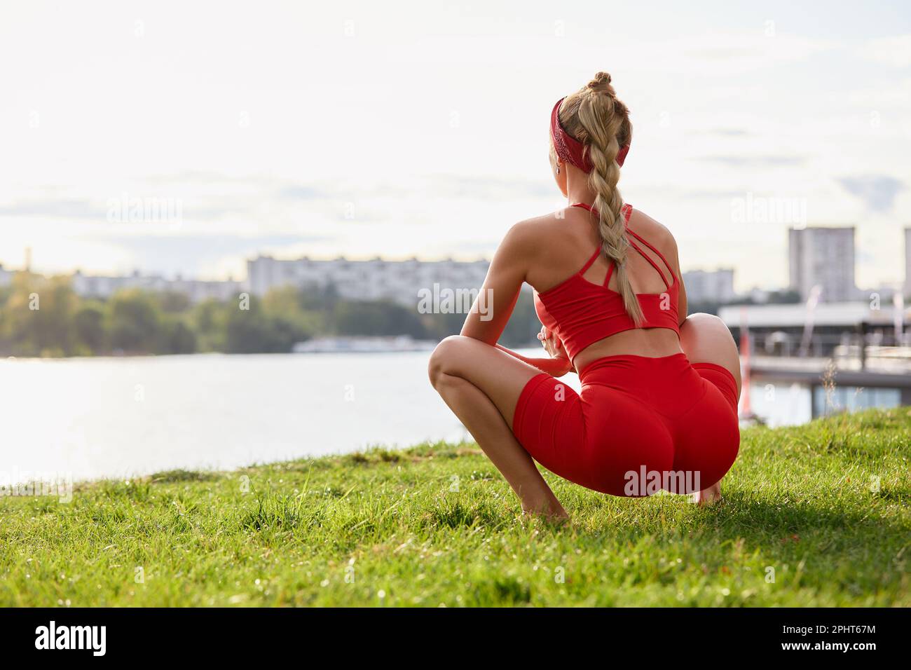 A woman does animal flow exercises in a red suit outdoors at dawn ...