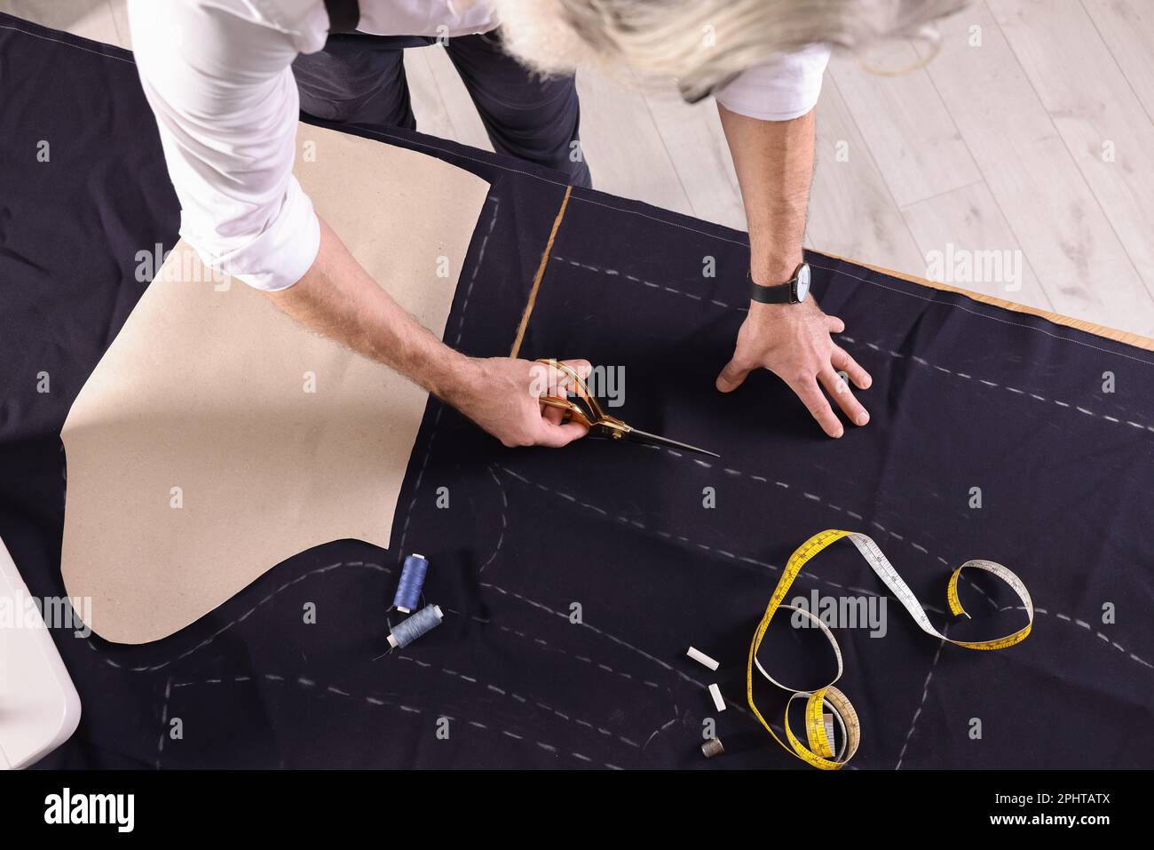 Professional tailor cutting fabric by following chalked sewing pattern ...