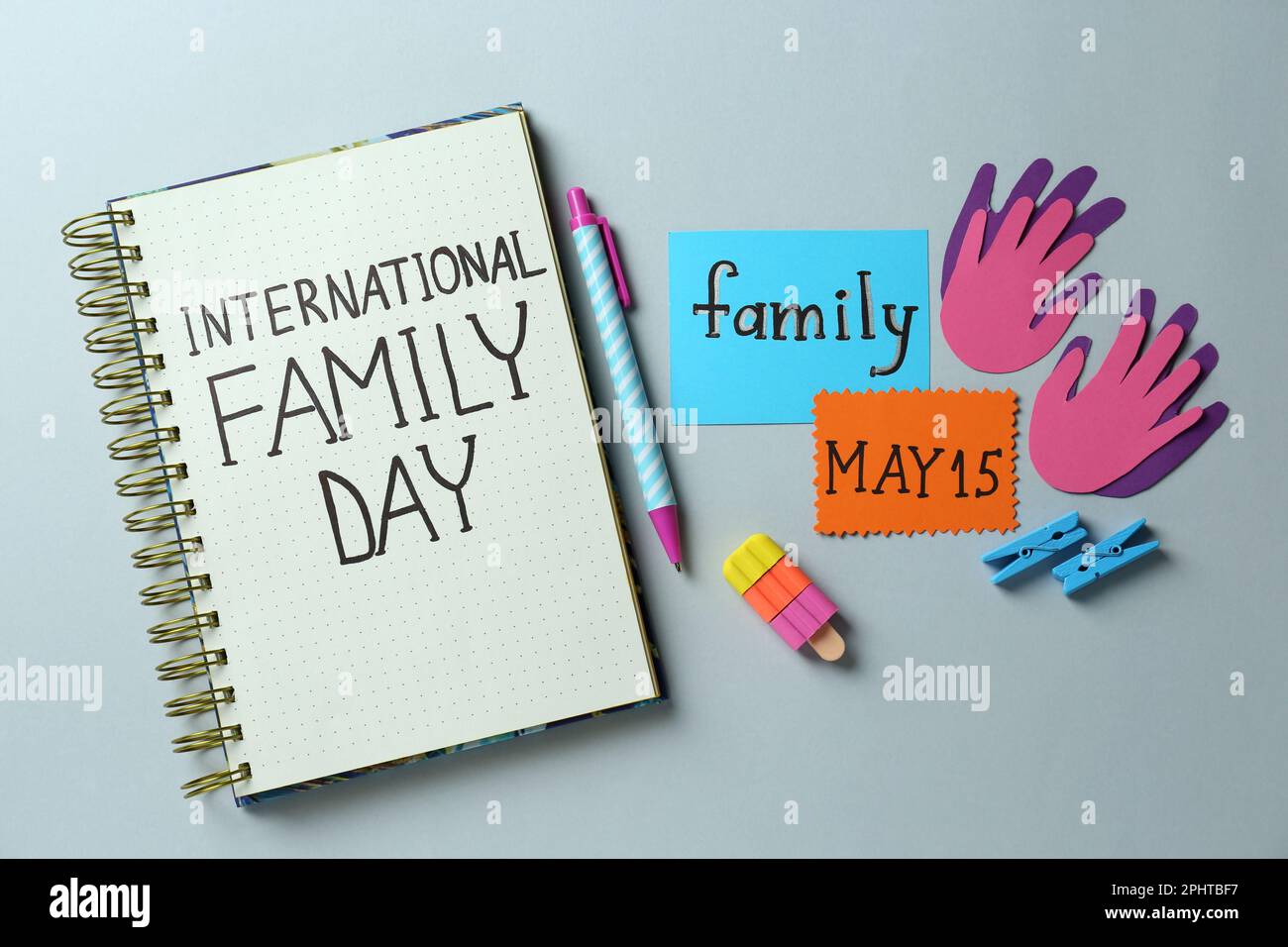 Notebook with text International Family Day May, paper hand cutouts and ...