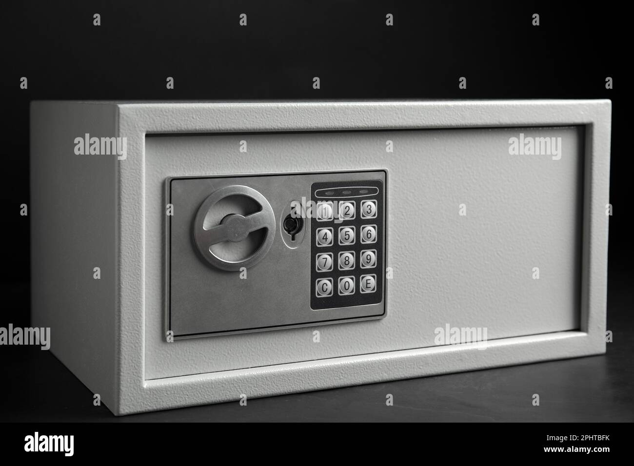 Steel safe with electronic lock on grey table against black background ...