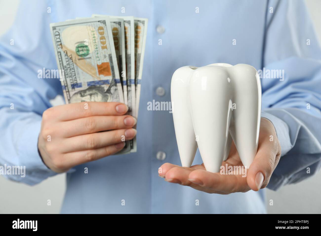 Woman holding ceramic model of tooth and dollar banknotes on light ...