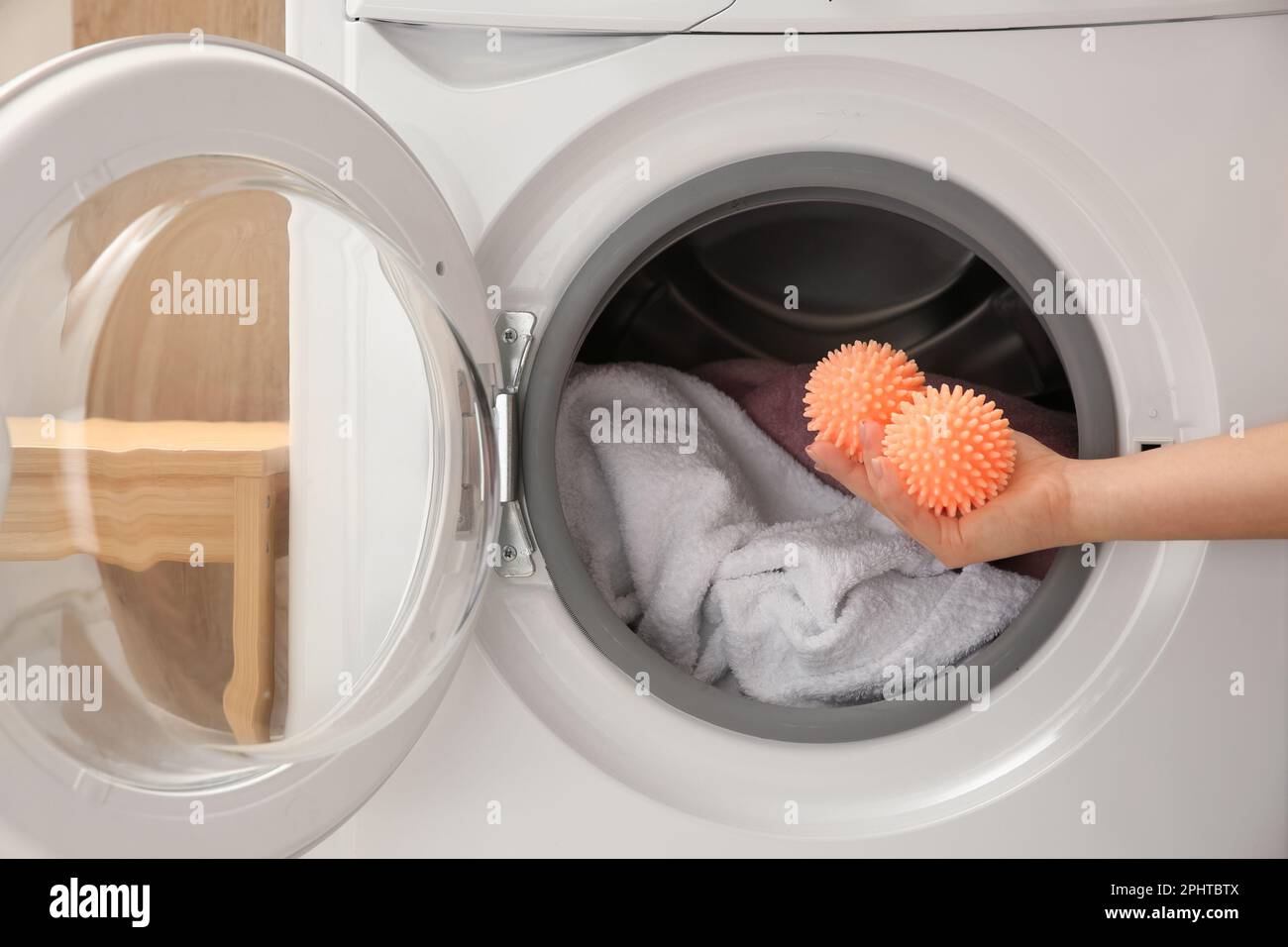 Woman putting dryer balls into washing machine, closeup Stock Photo - Alamy