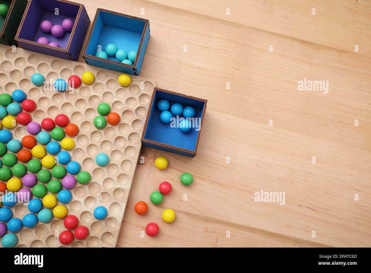 Wooden sorting board and boxes with colorful balls on table, flat lay ...