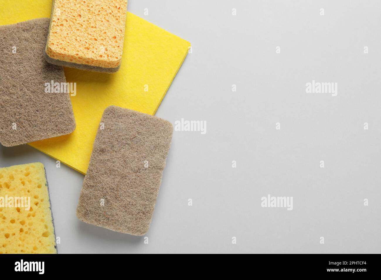 New sponges and rag on light grey background, flat lay. Space for text ...