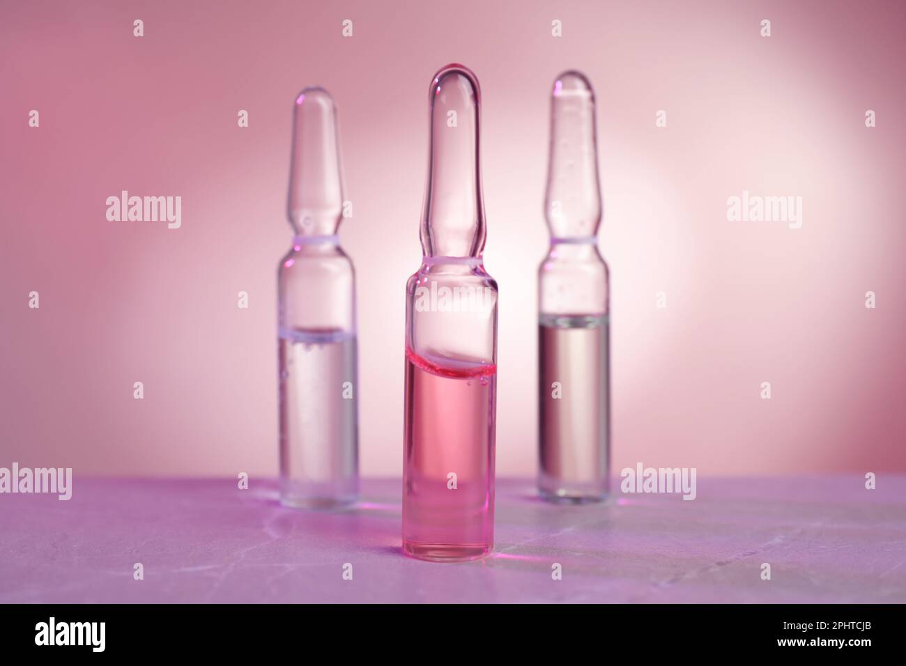 Pharmaceutical ampoules with medication on grey table against color ...