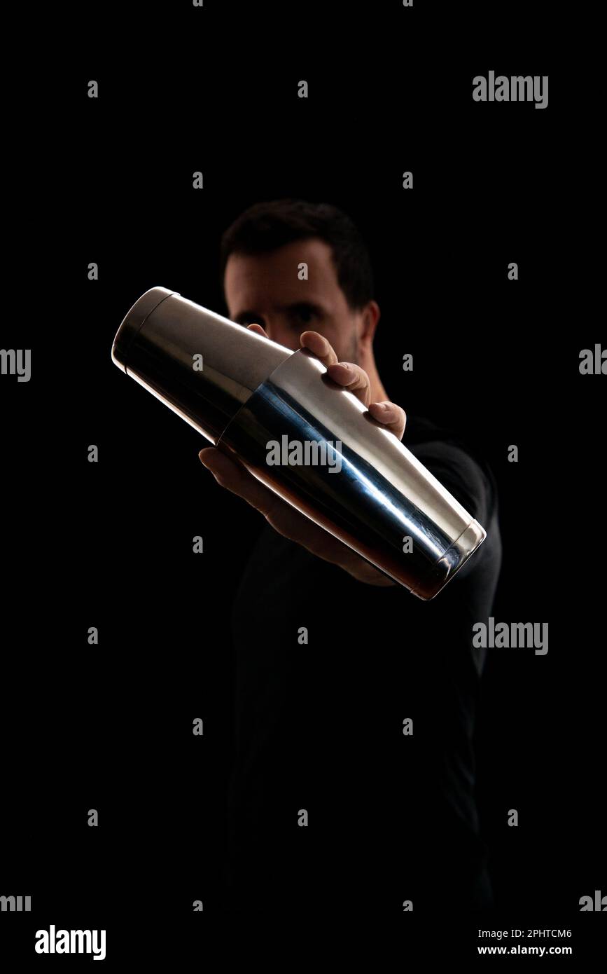 Portrait of a young man with a shaker isolated on a black background ...