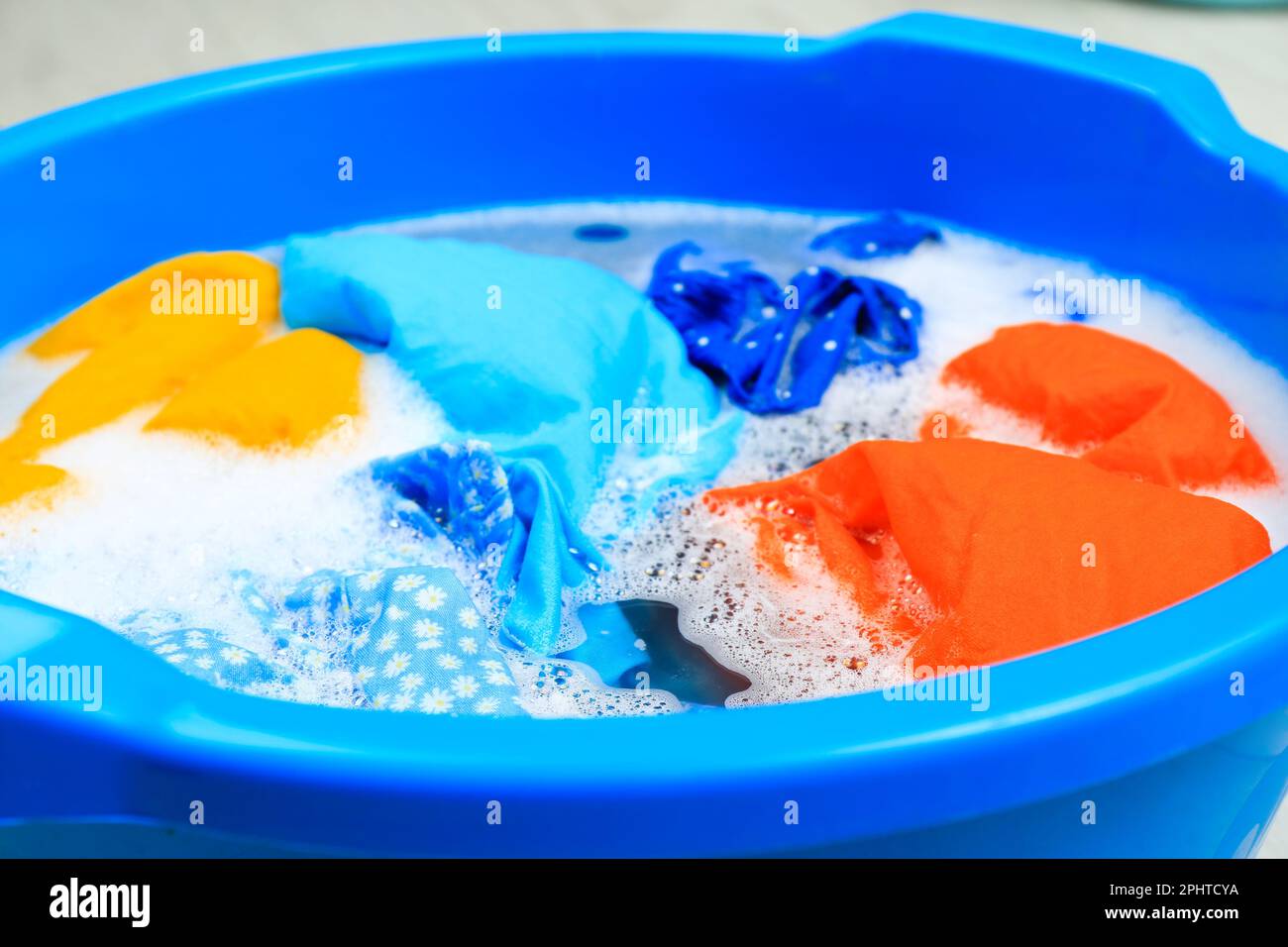 Basin with colorful clothes in suds, closeup. Hand washing laundry ...