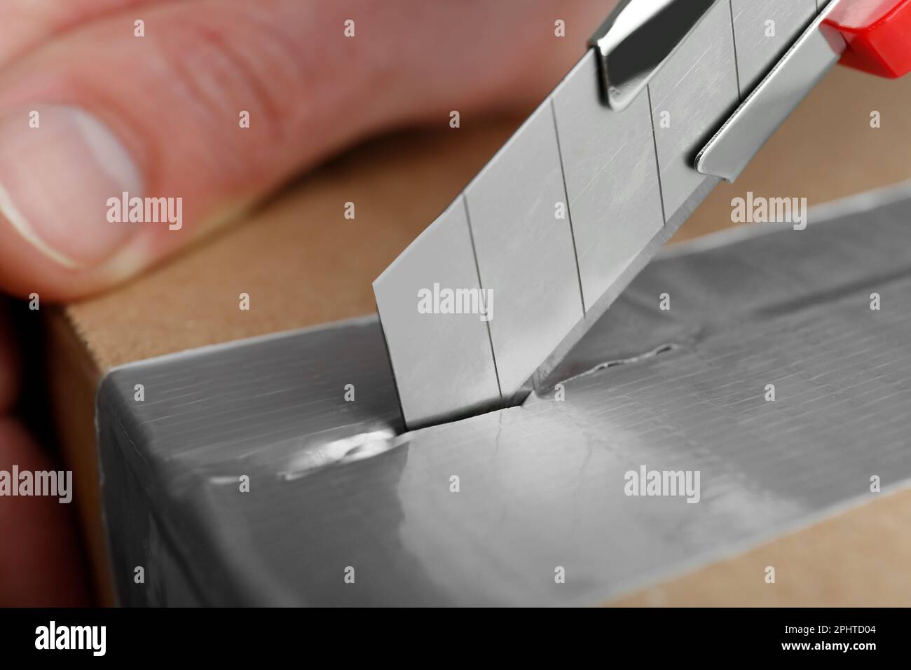 Man using utility knife to open parcel, closeup Stock Photo - Alamy