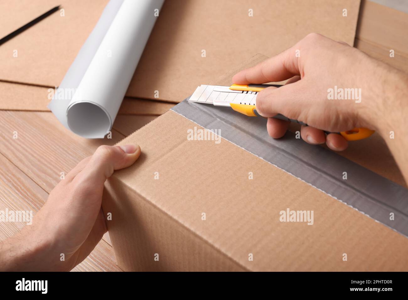 Man using utility knife to open parcel at wooden table, closeup Stock ...