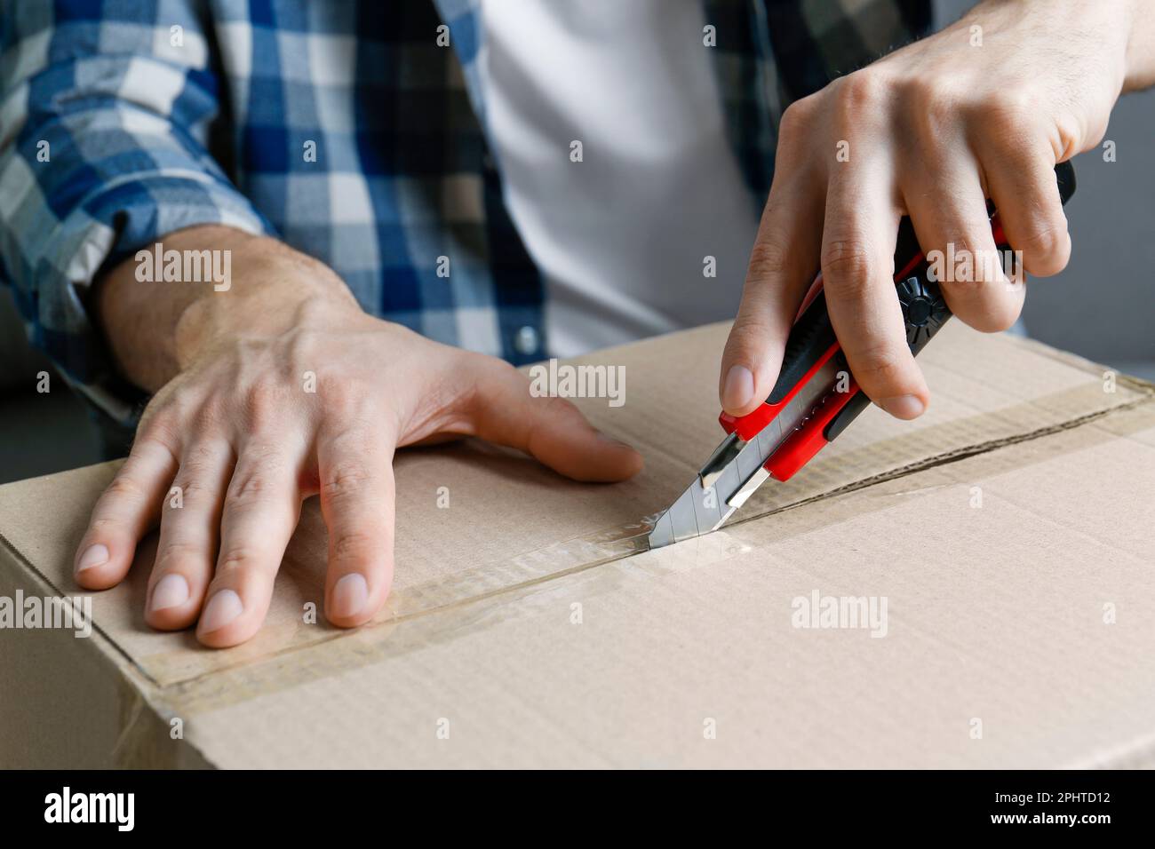 Man using utility knife to open parcel, closeup Stock Photo - Alamy